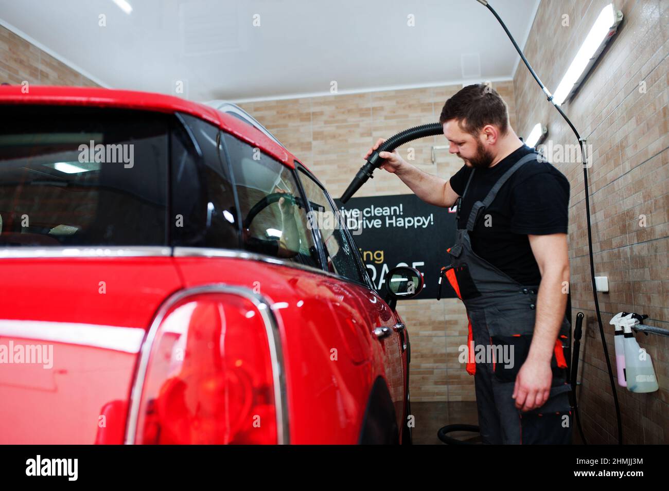Man worker drying red car in detailing garage after washing Stock Photo ...