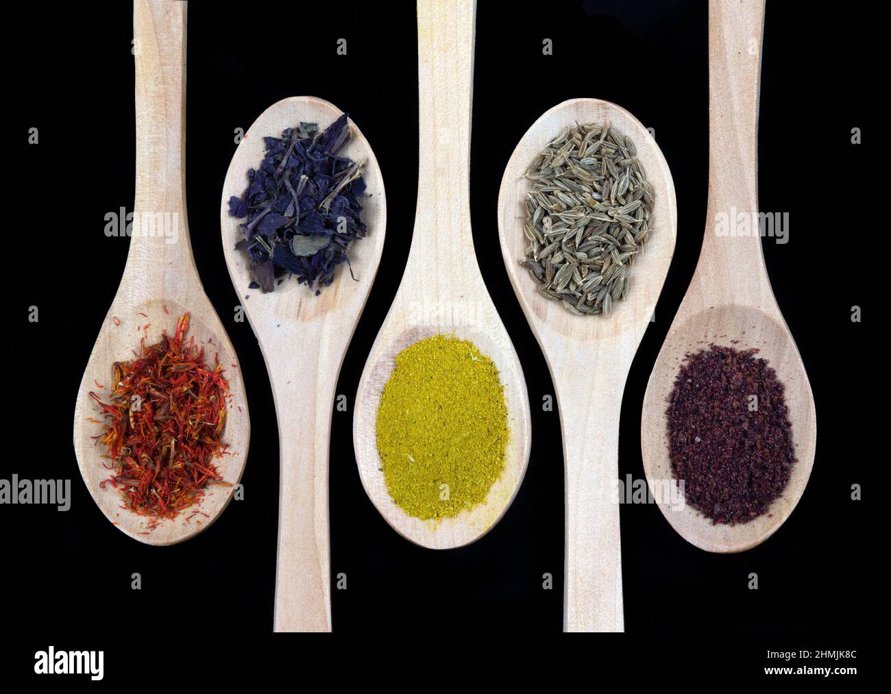 Spices in wooden spoon isolated on black background Stock Photo - Alamy