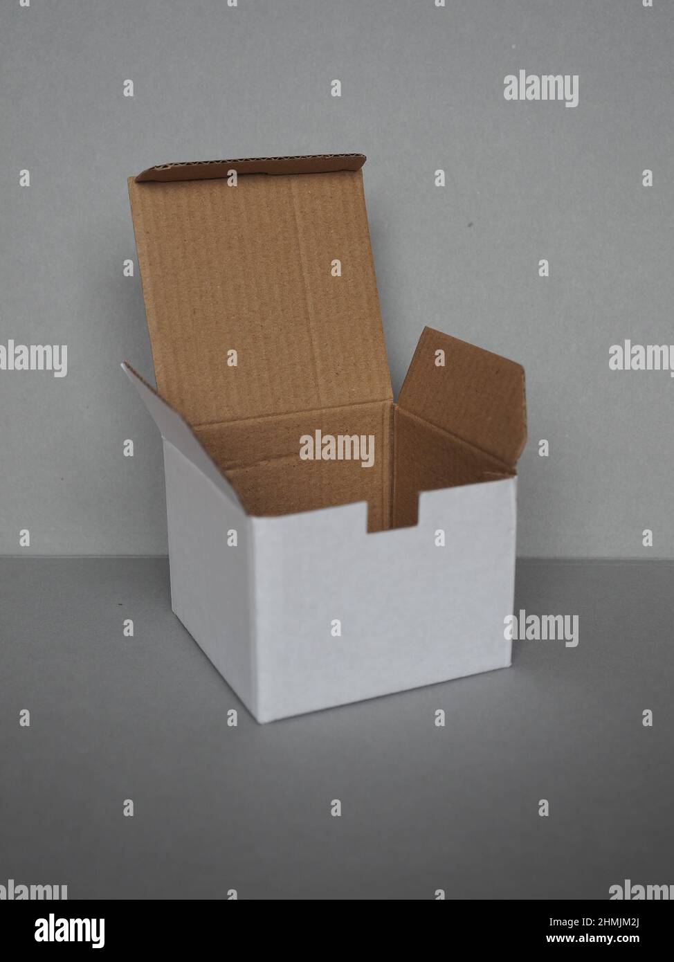 empty cardboard box in front of grey wall Stock Photo - Alamy