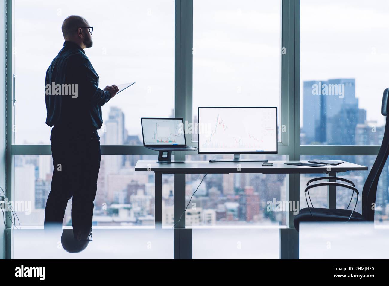 Entrepreneur with tablet near computers with charts on office table ...