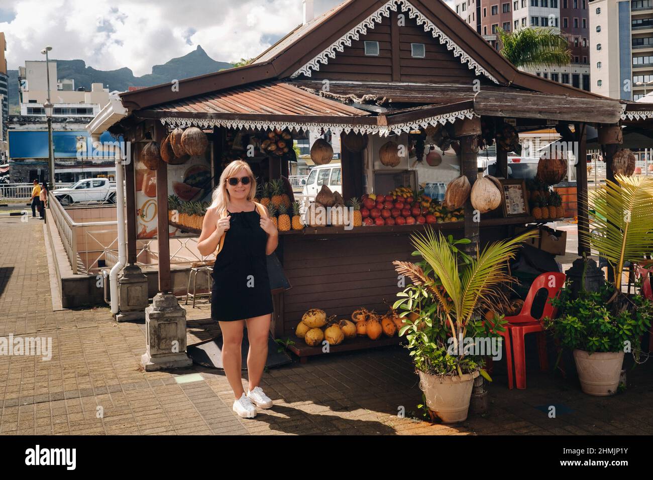 A tourist girl stands near a fruit counter in Port Louis, Mauritius ...
