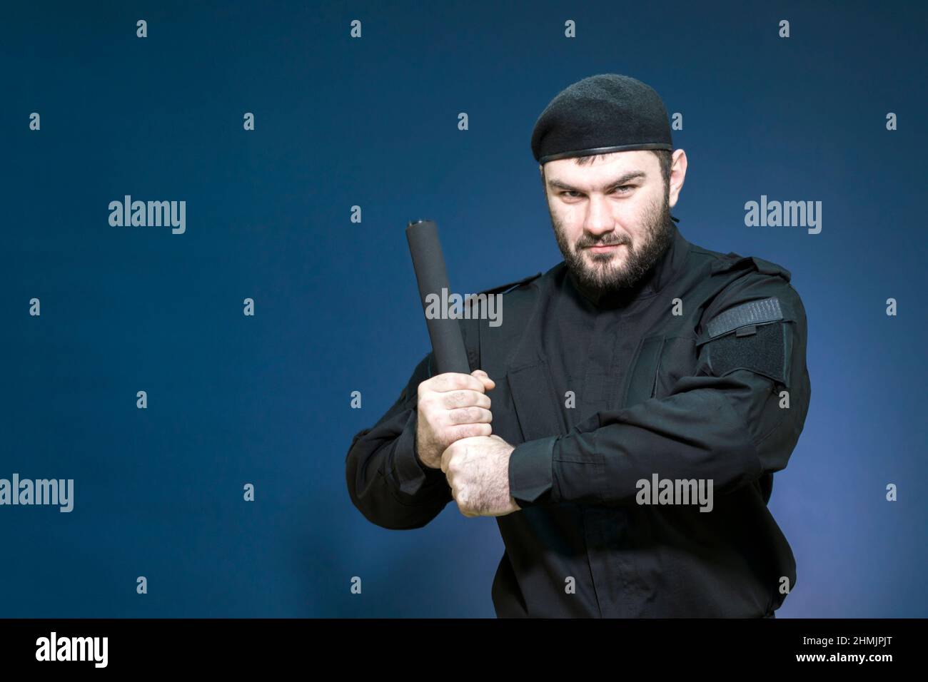 A male security guard in a black uniform and a cap took a protective ...