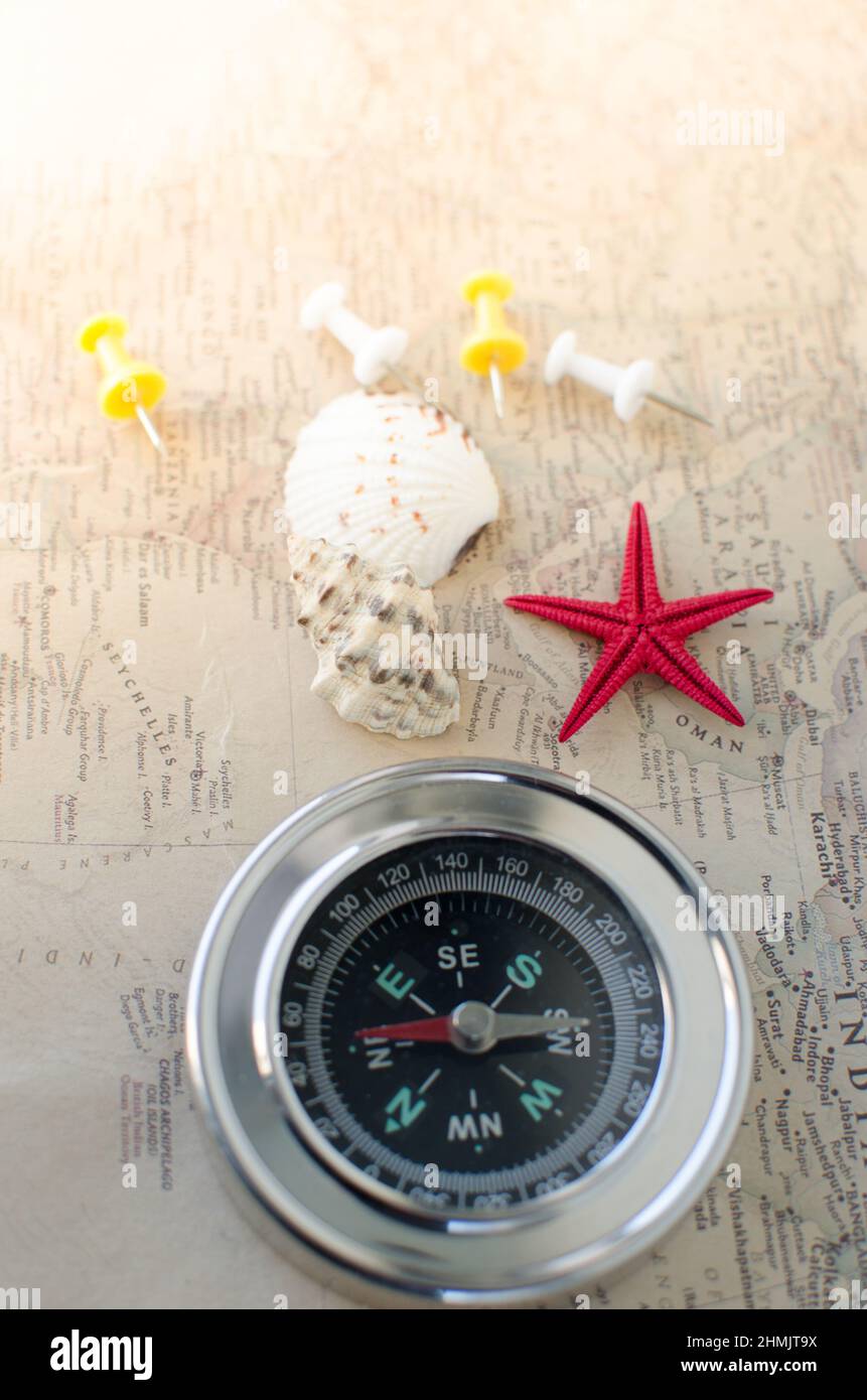 Compass, button, starfish and shells on the old map in the rays of the ...