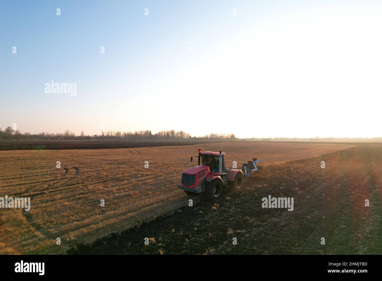 Tractor Plowing field on sunset. Red Tractor with Plough on Plowed ...