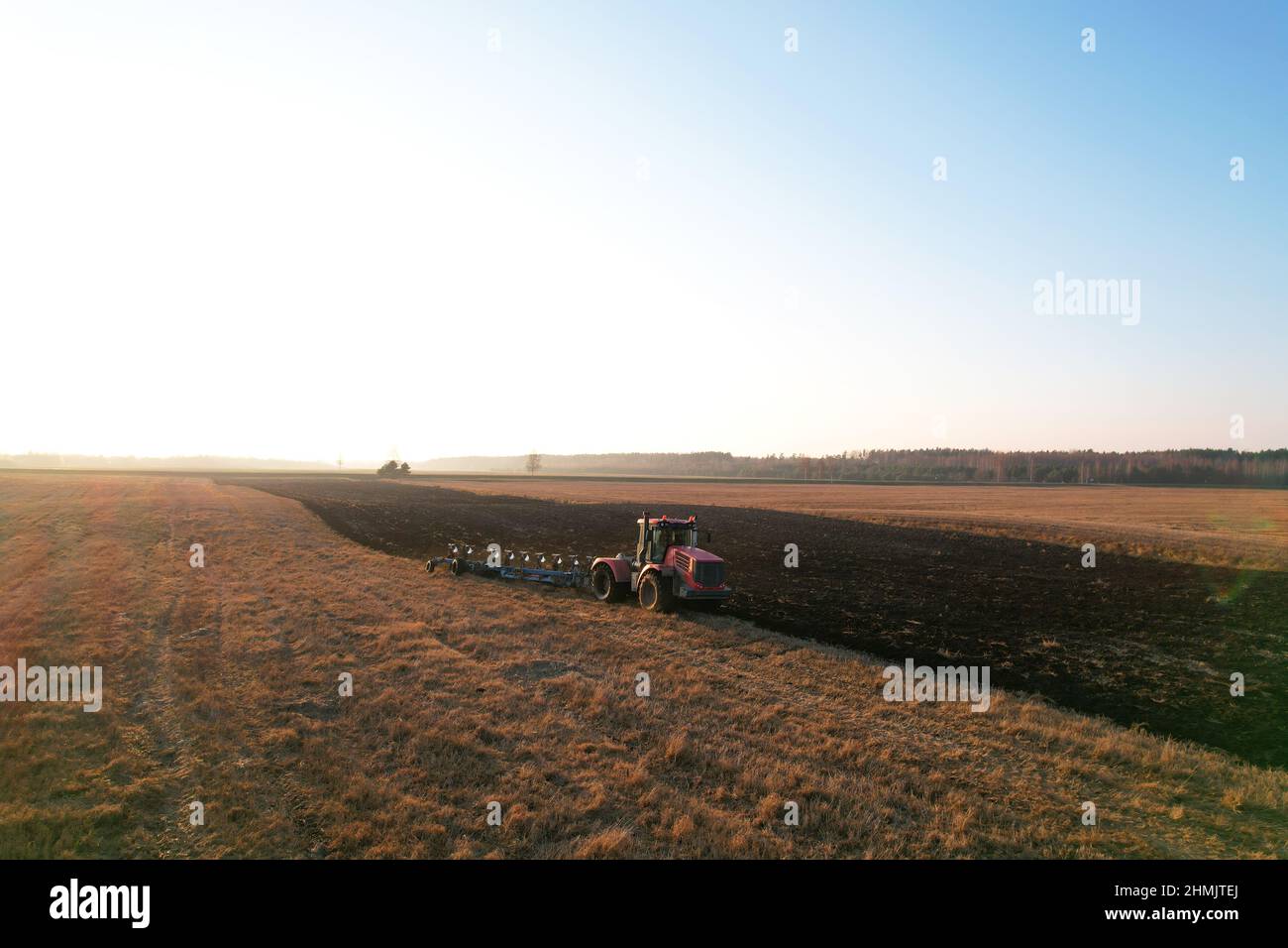 Tractor Plowing field on sunset. Red Tractor with Plough on Plowed ...