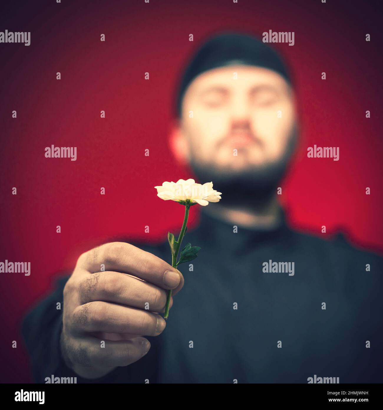 Military. A male guard in black uniform and a cap holds a flower ...