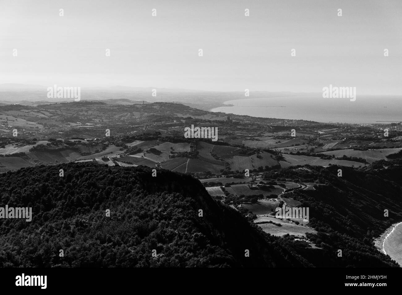 Greyscale bird's eye view of the fields and nature landscape in Italy ...