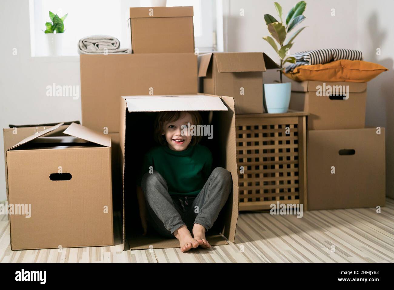 Boy hiding in inside a huge cardboard box. He is playing and looking ...