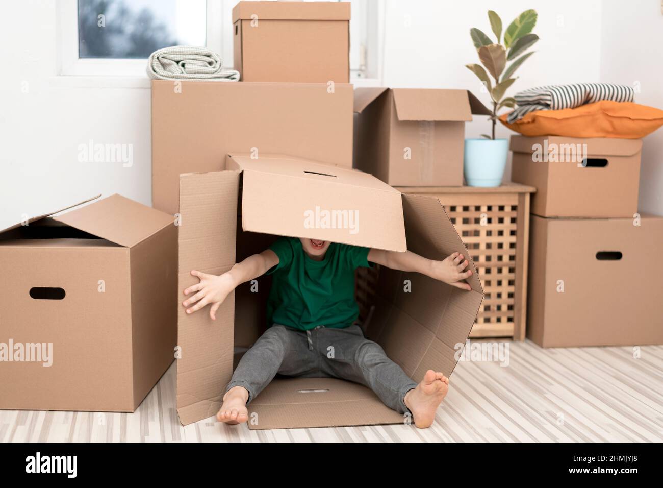 Excited little boy jumping inside a huge cardboard box. He is playing ...