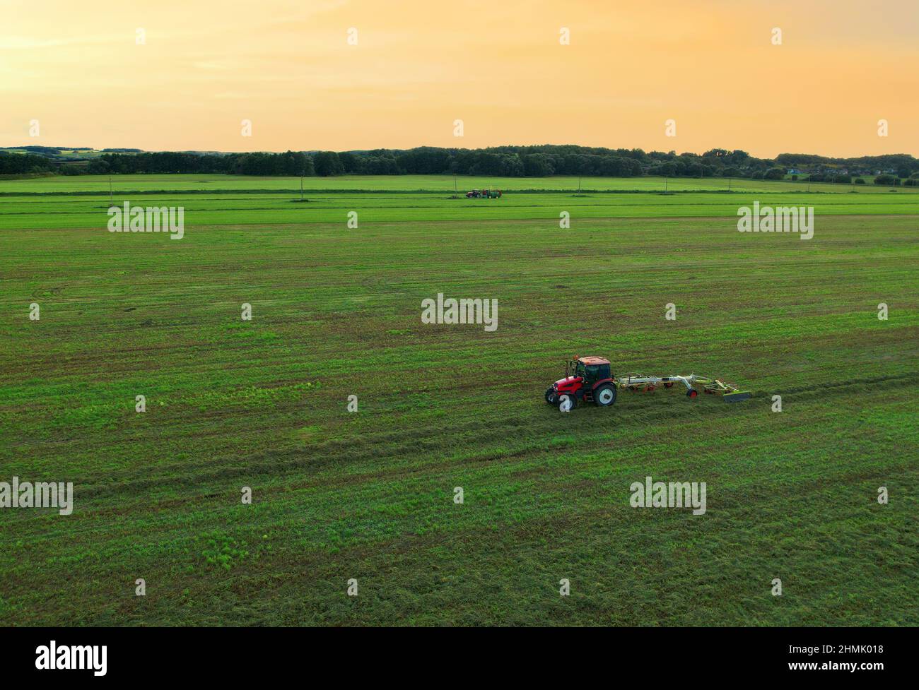 Tractor raking grass for silage harvesting. Agriculture farm machinery ...