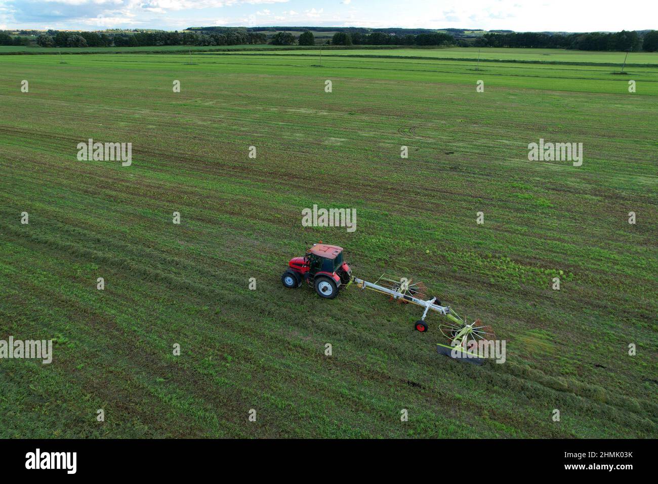 Tractor raking grass for silage harvesting. Agriculture farm machinery ...