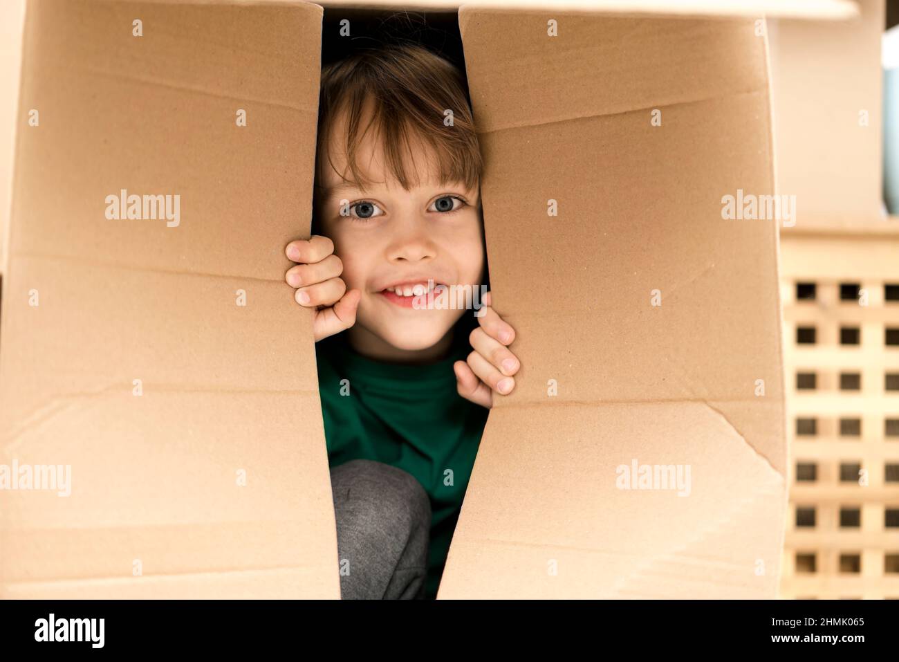 Boy hiding in inside a huge cardboard box. He is playing and peeking ...