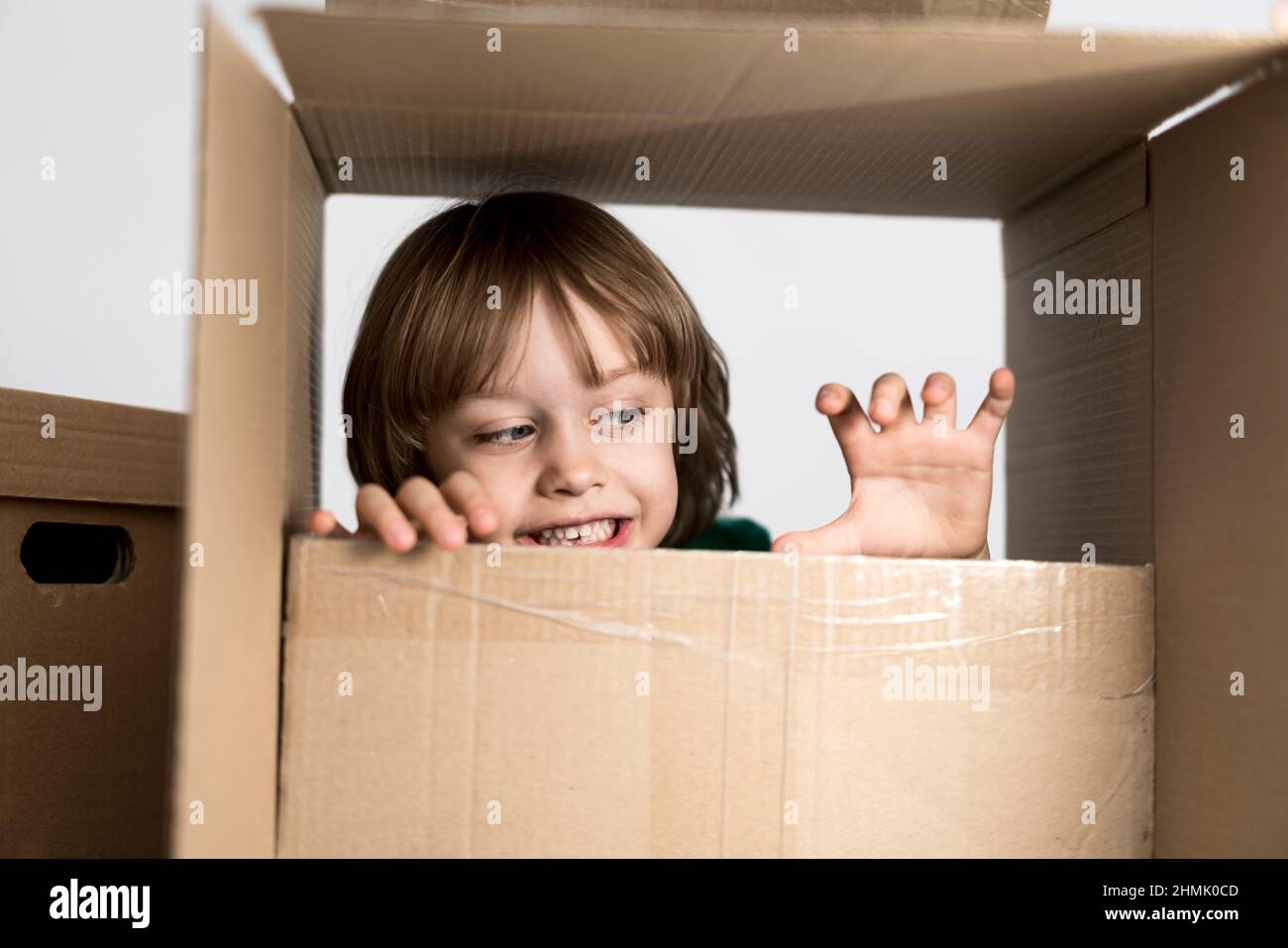 Excited little boy jumping inside a huge cardboard box. He is playing ...