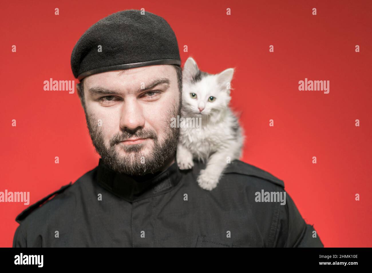 A male security guard in a black uniform and a cap holds a cute fluffy ...
