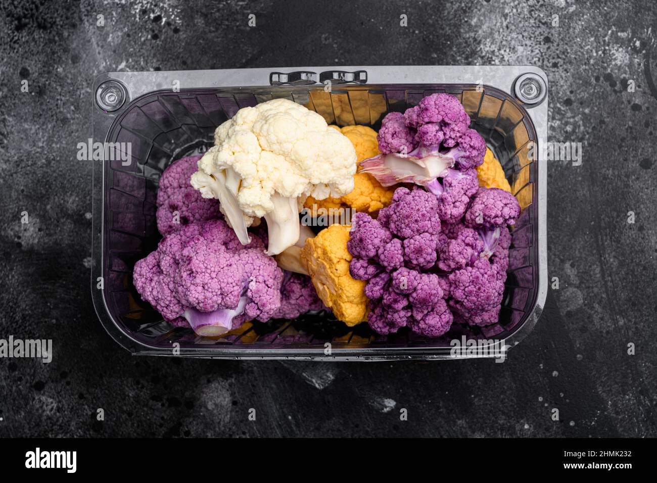 Fresh heads cleaned cauliflower set, in container, on black dark stone ...