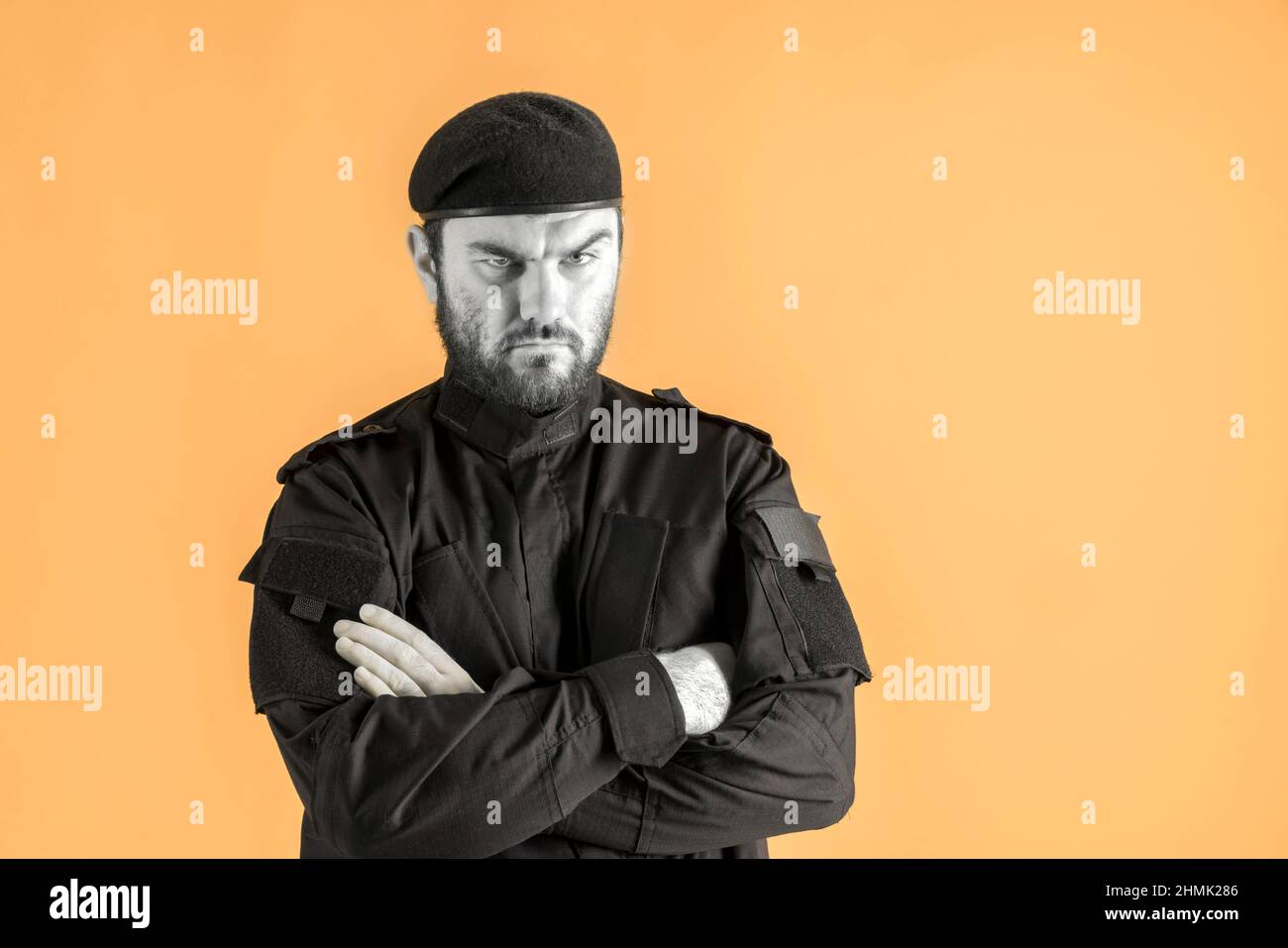 A male security guard in a black uniform and a cap with a serious ...
