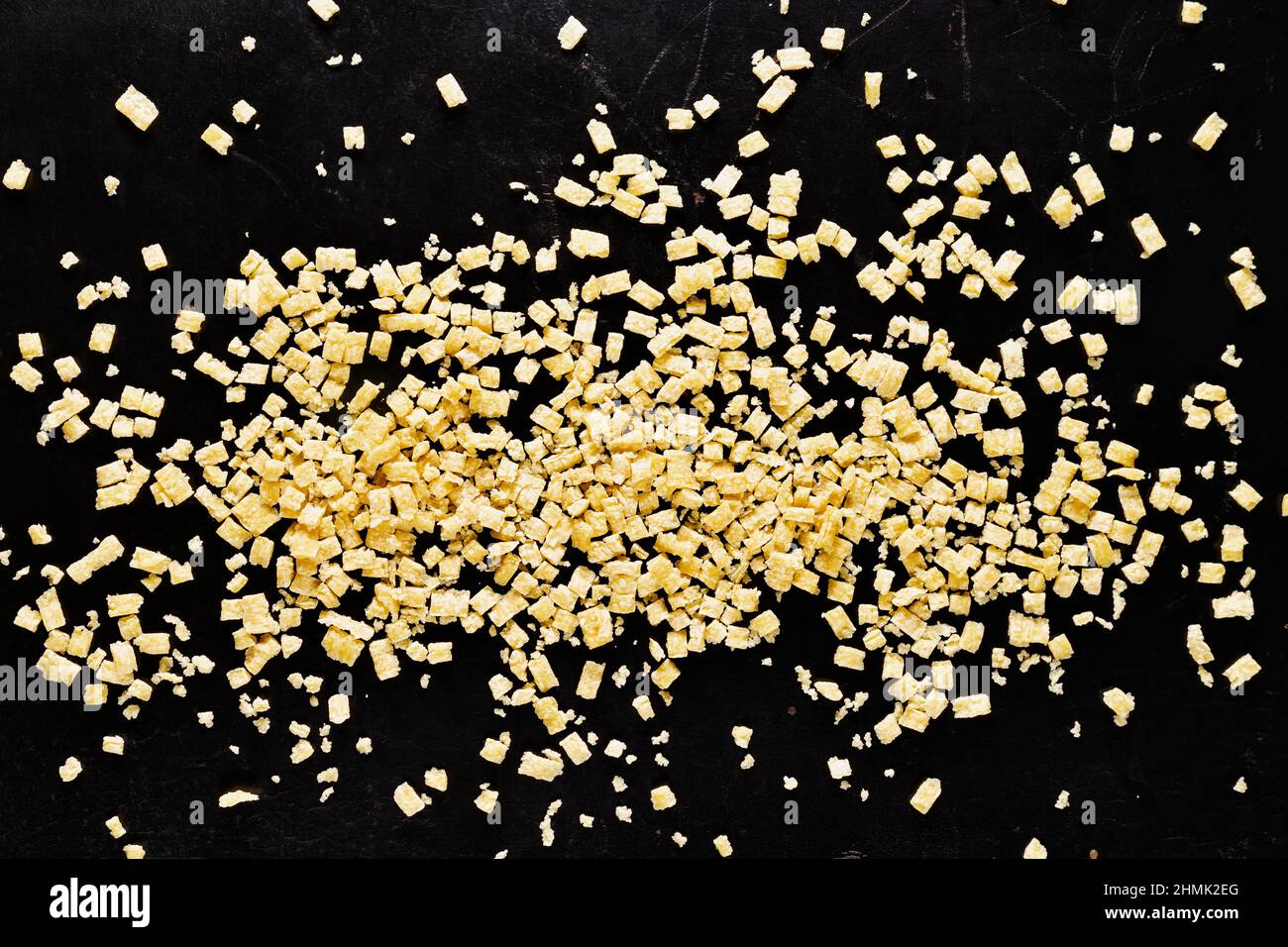 Small flat squares egg pasta called grattini on black background,yellow ...
