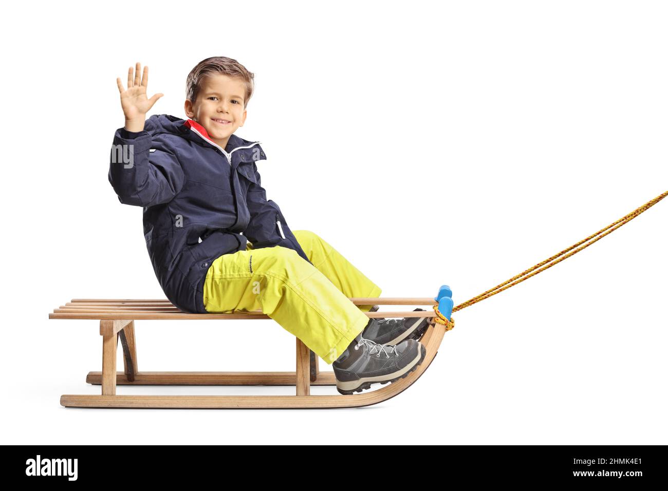 Full length profile shot of a boy sitting on a sleigh and waving ...