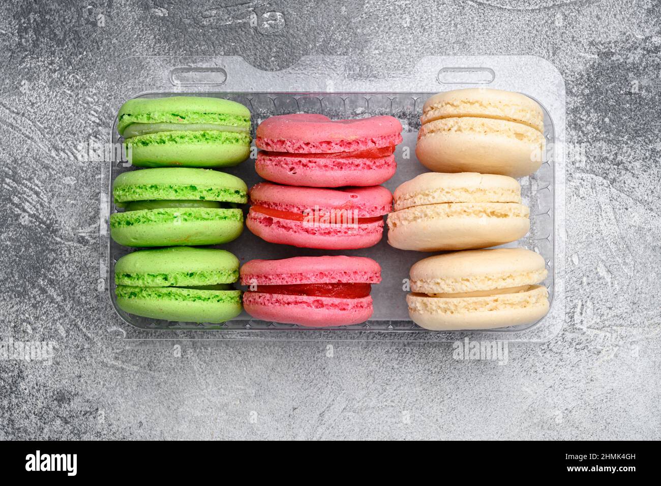 Sweet colorful macarons set, in plastic pack, on gray stone table ...