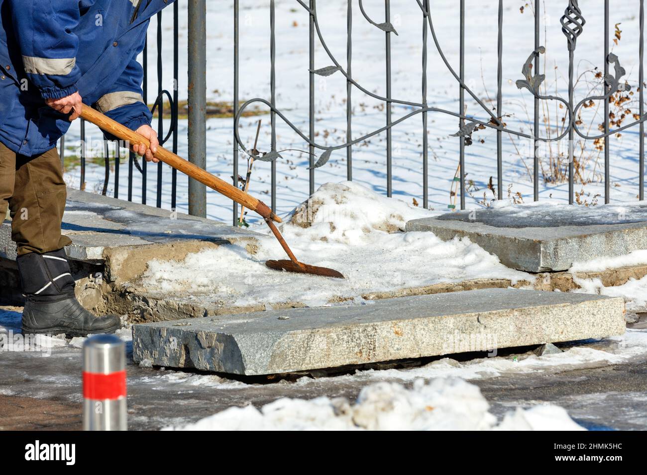 On a clear winter day, a utility worker clears snow and ice from a ...