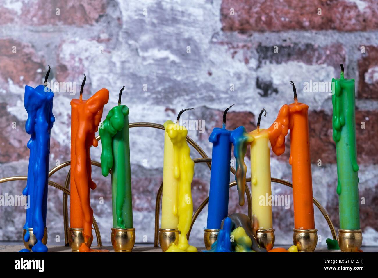 Candlestick with multi-colored candles on the background of a brick ...