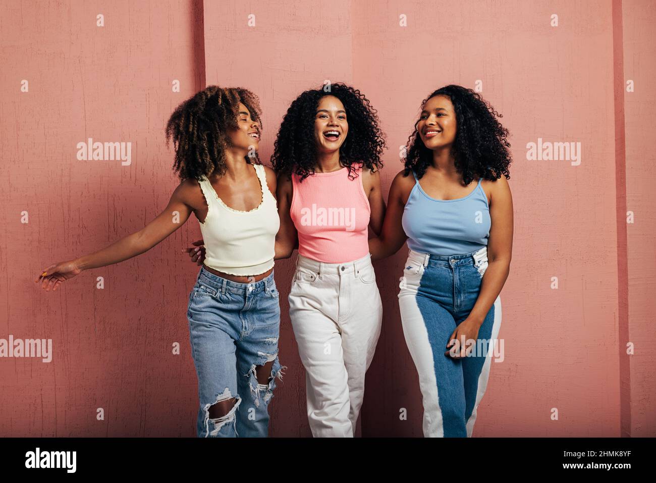Three happy women with curly hair walk together. Young females having ...