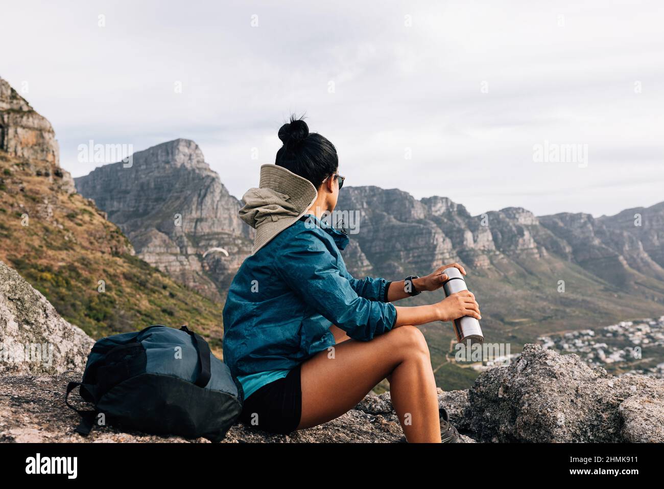 Female mountain climber looking at the view while sitting on a rock ...