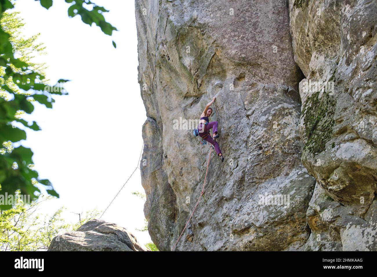 Determined girl climber clambering up steep wall of rocky mountain ...