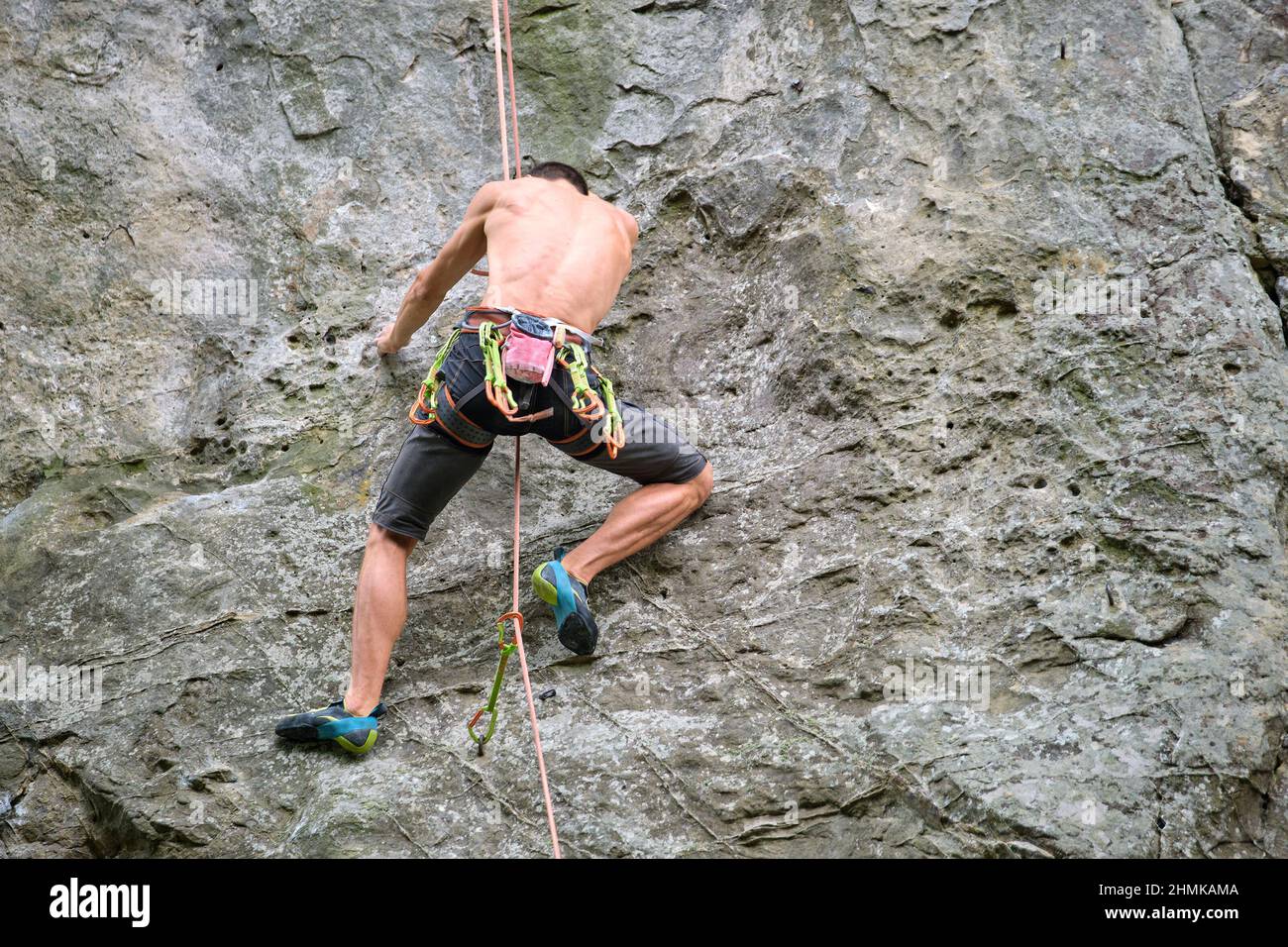 Strong male climber climbing steep wall of rocky mountain. Sportsman ...