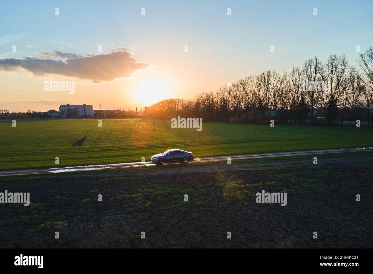 Aerial view of sedan car driving fast on dirt road at sunset. Traveling ...