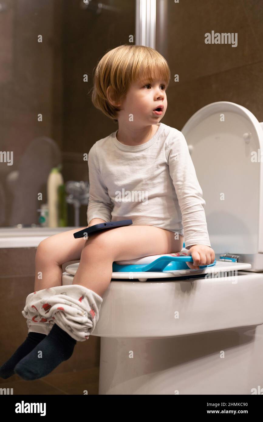 Cute toddler boy, sitting on toilet, using mobile phone Stock Photo - Alamy