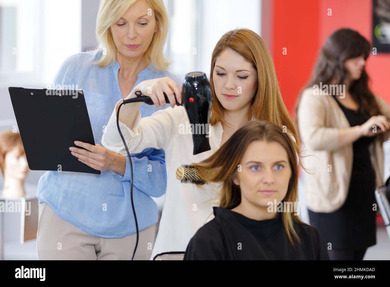 teacher helping students training to become hairdressers Stock Photo ...