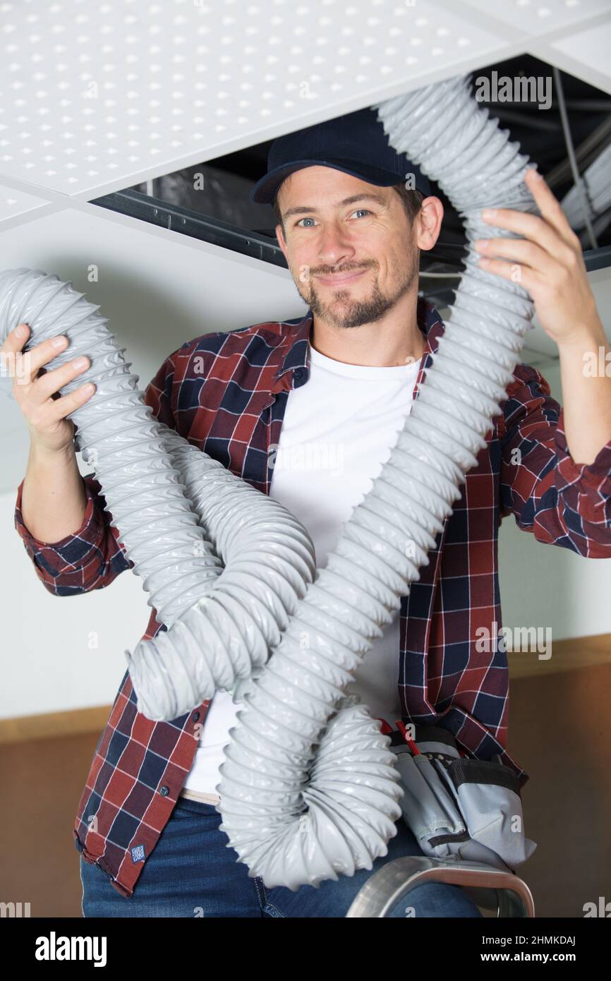 man fitting flexible hose above suspended ceiling Stock Photo - Alamy