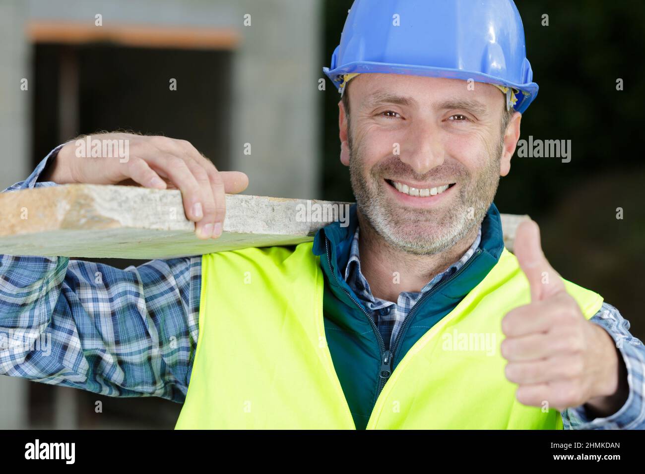 carpenter builder on strict face carries wooden beam on shoulder Stock ...