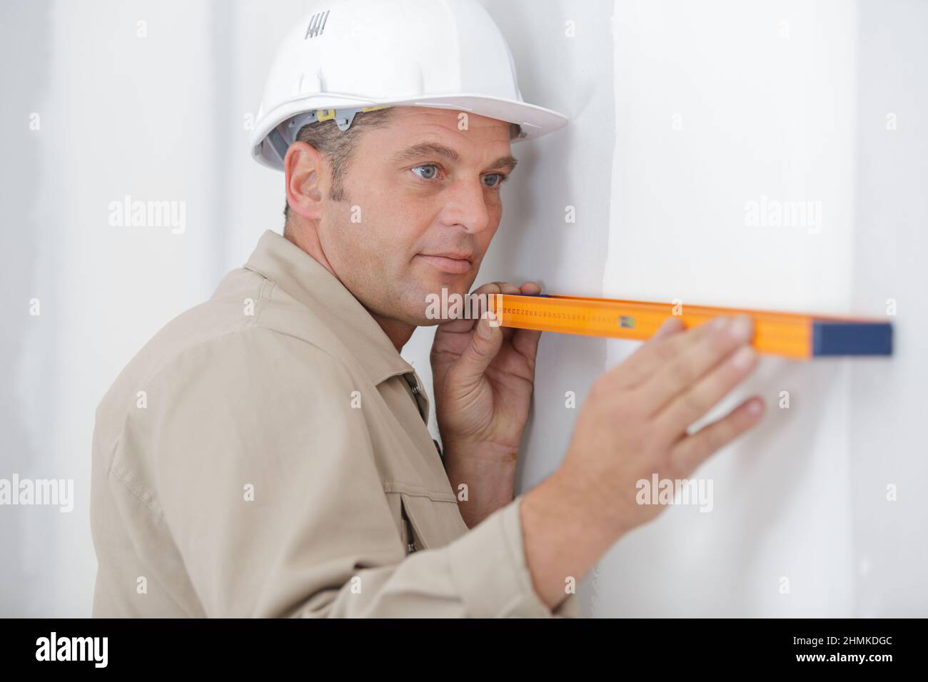professional worker in helmet is measuring wall with level Stock Photo ...