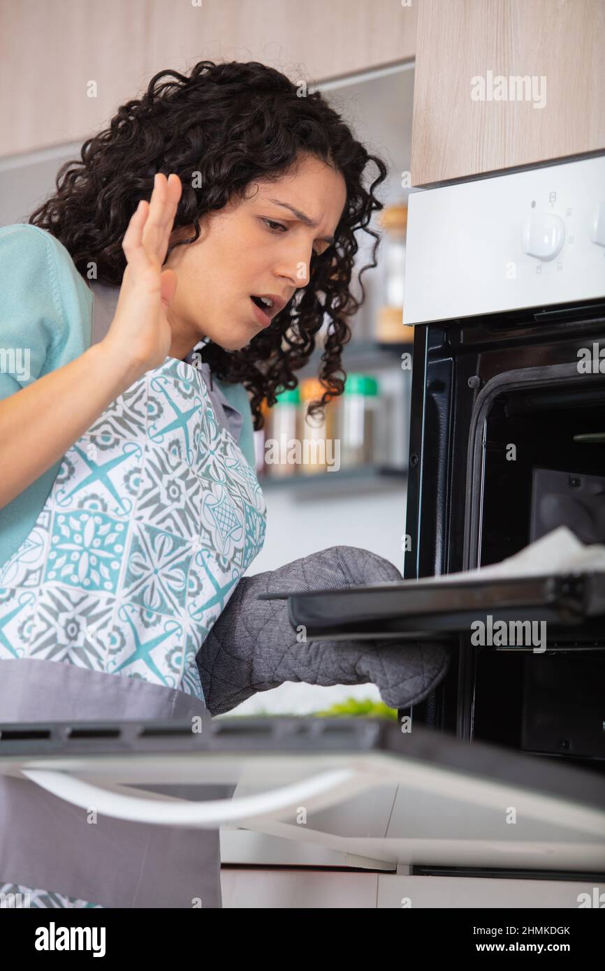 woman looking in shock at burnt food in the oven Stock Photo - Alamy