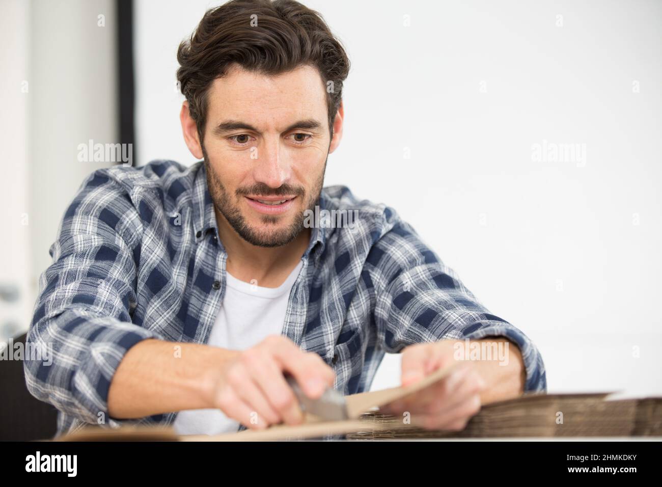 man cuts a box with a stationery knife Stock Photo - Alamy