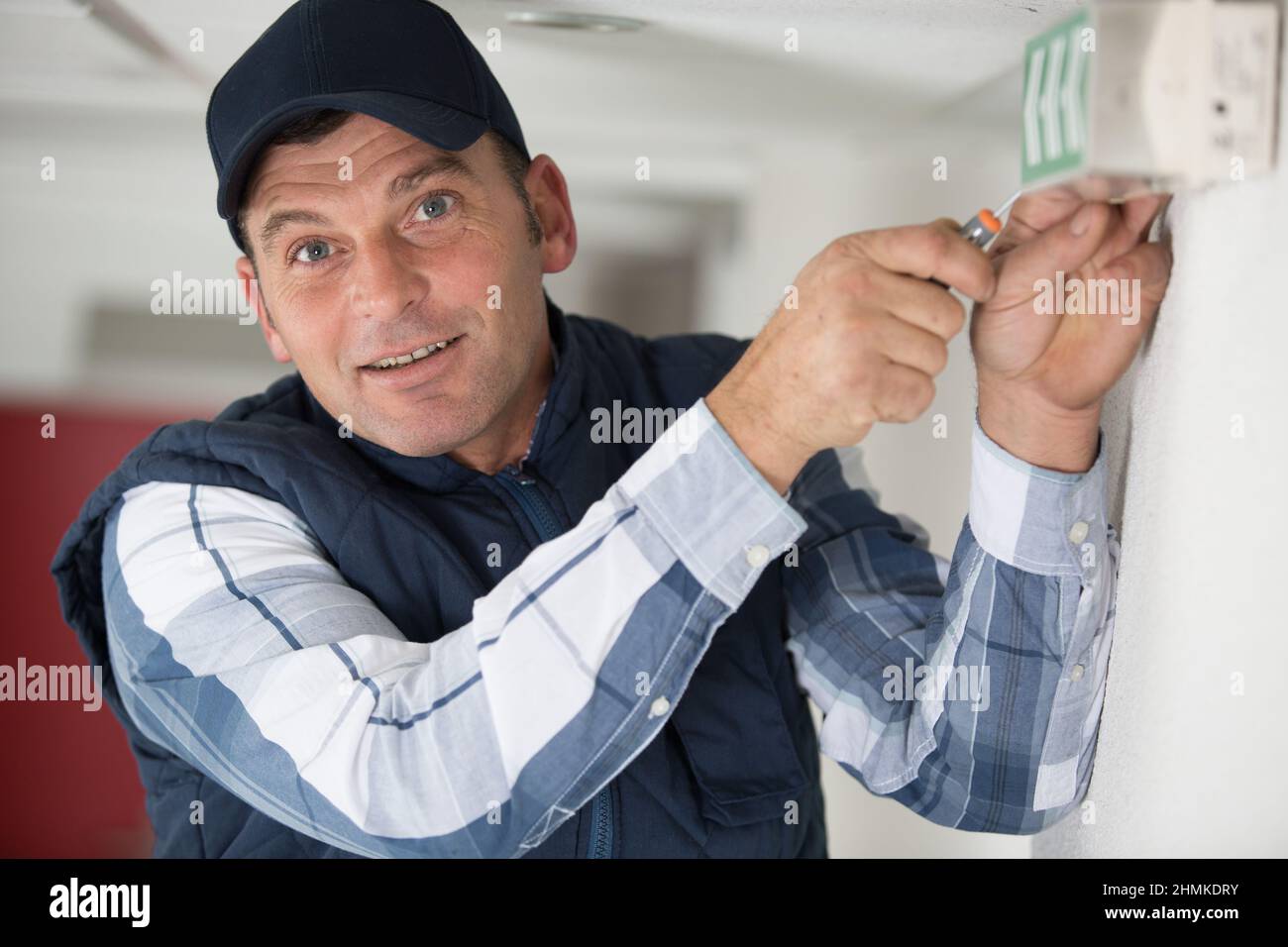 man fixing exit sign to wall Stock Photo - Alamy