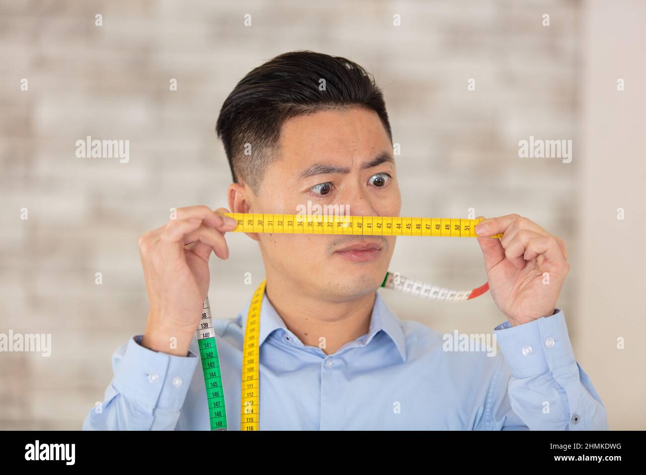 man holding a tape measure in front of his face Stock Photo - Alamy