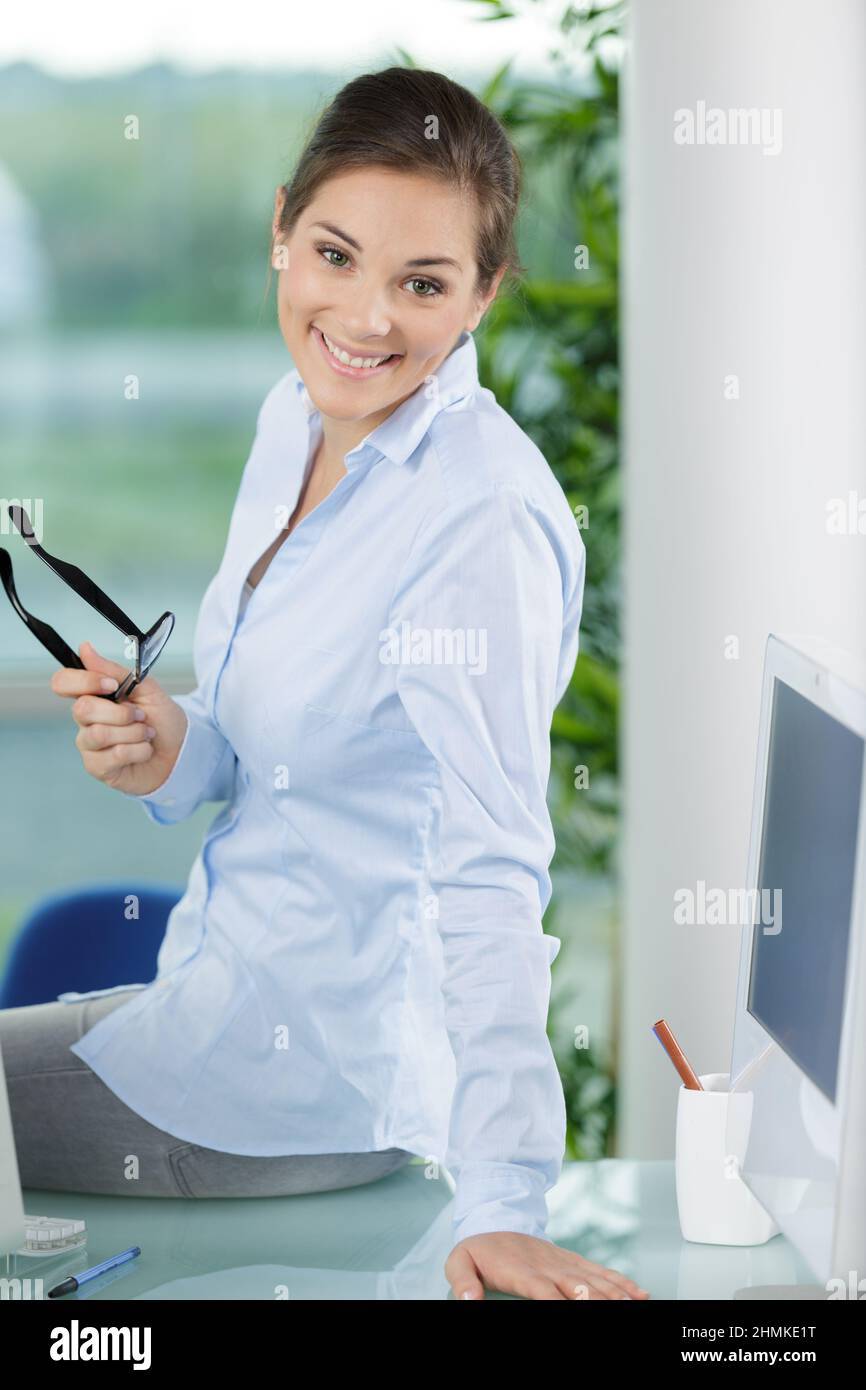 secretary sat on desk holding her eyeglasses Stock Photo - Alamy