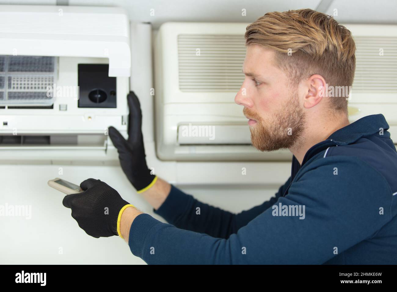 man checking air conditioner mounted on wall Stock Photo - Alamy