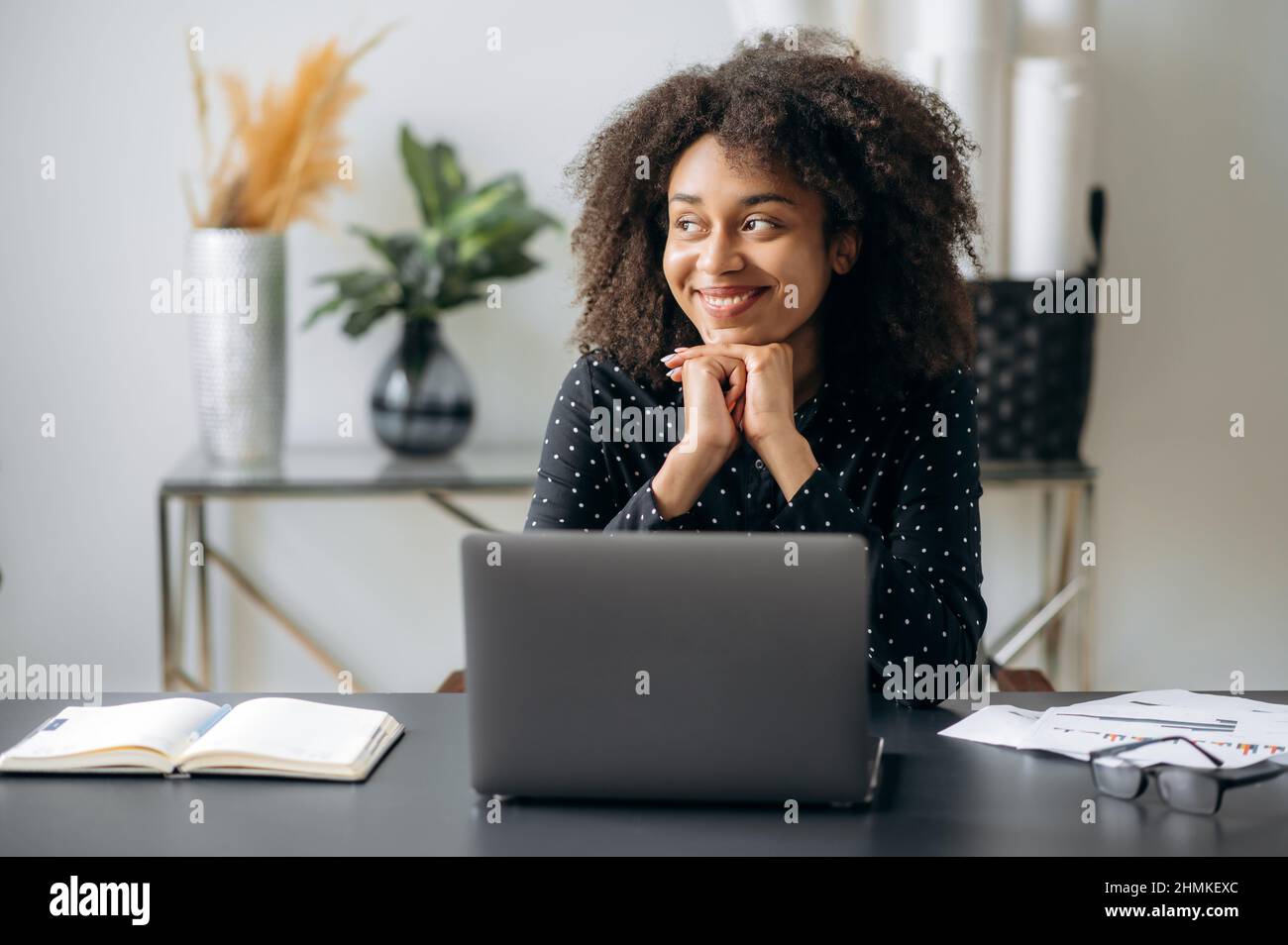Satisfied dark-skinned curly-haired young woman, office worker, manager ...