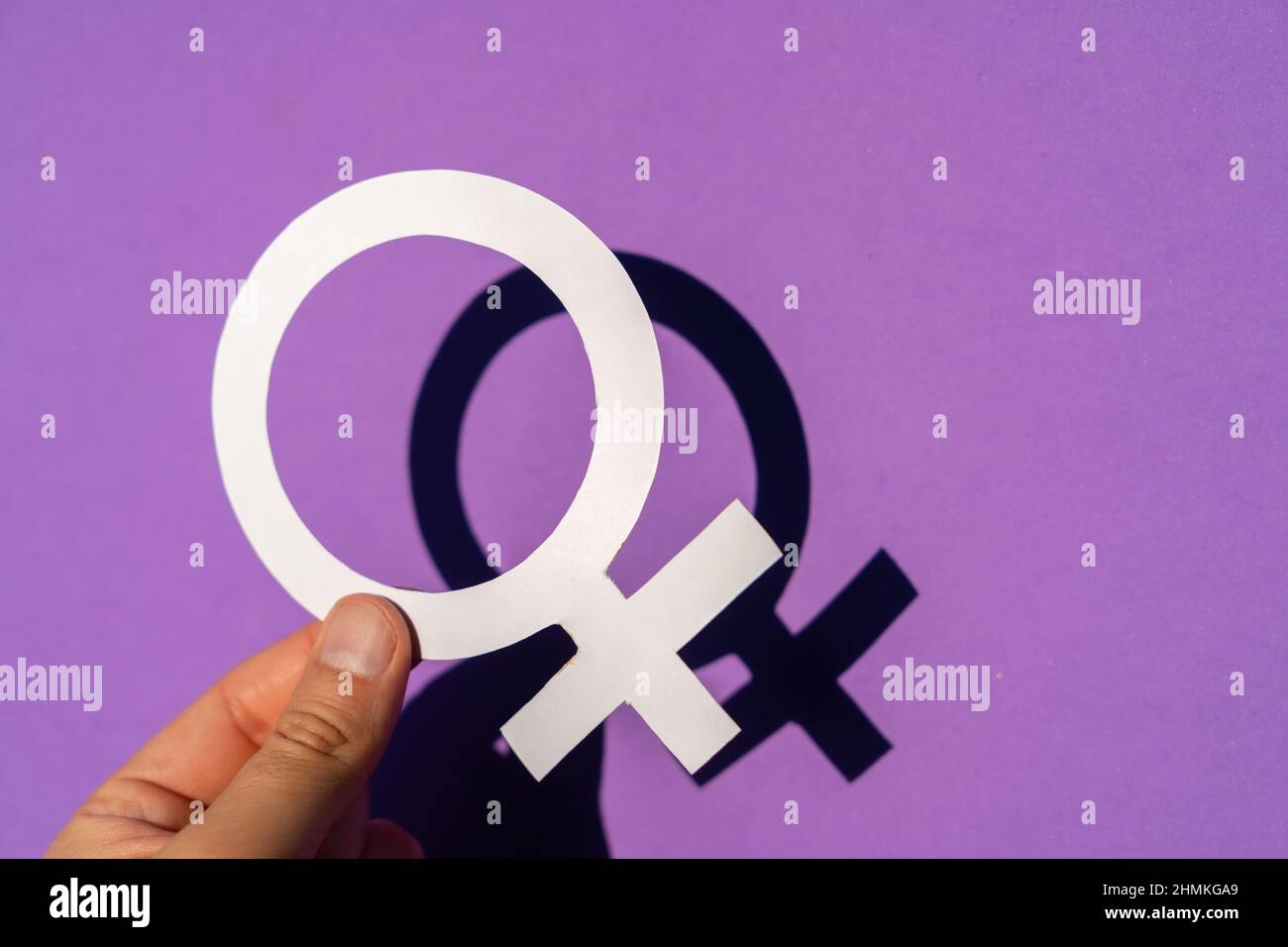Closeup of a person holding the female symbol on a purple background ...