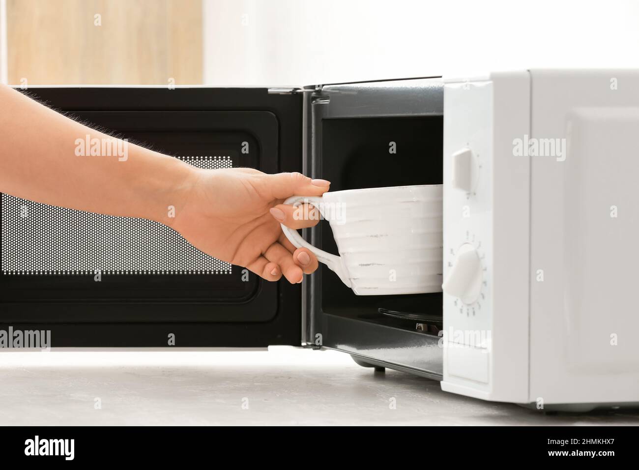 Woman taking cup from microwave oven, closeup Stock Photo - Alamy