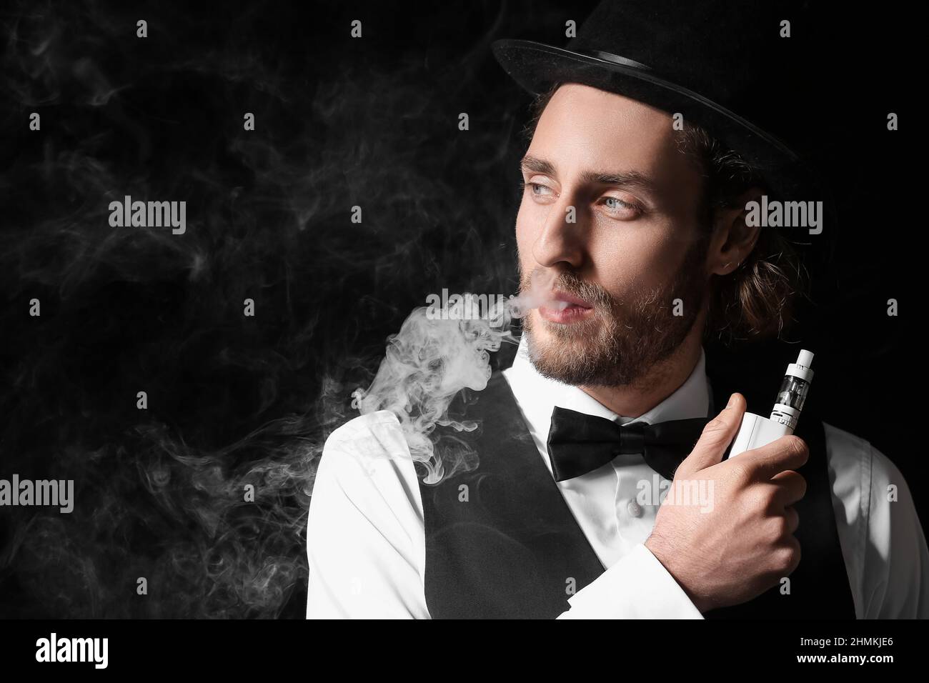 Vaping young man on black background Stock Photo - Alamy