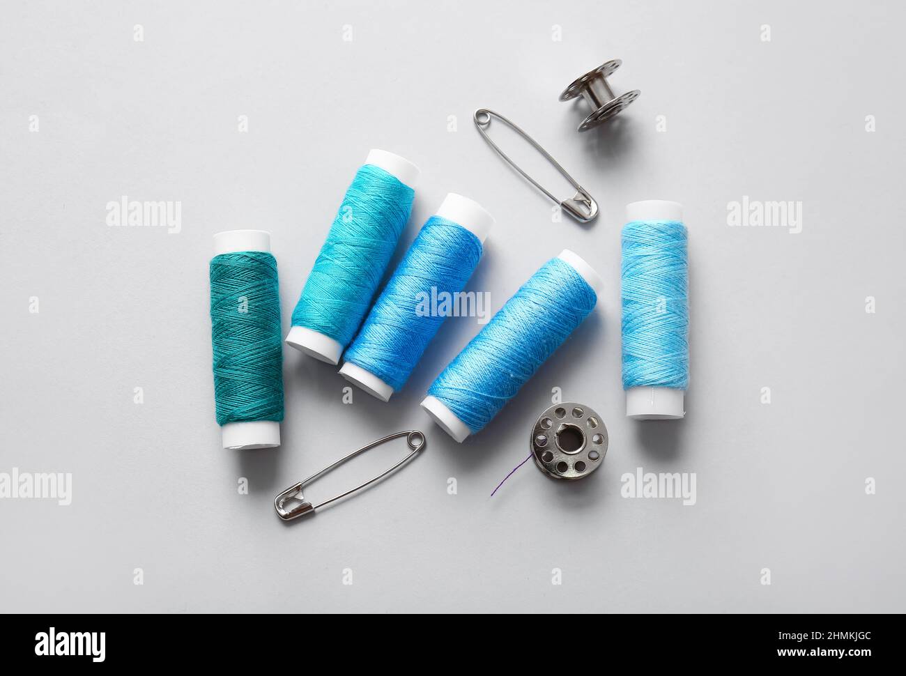Thread spools and pins on light background Stock Photo - Alamy
