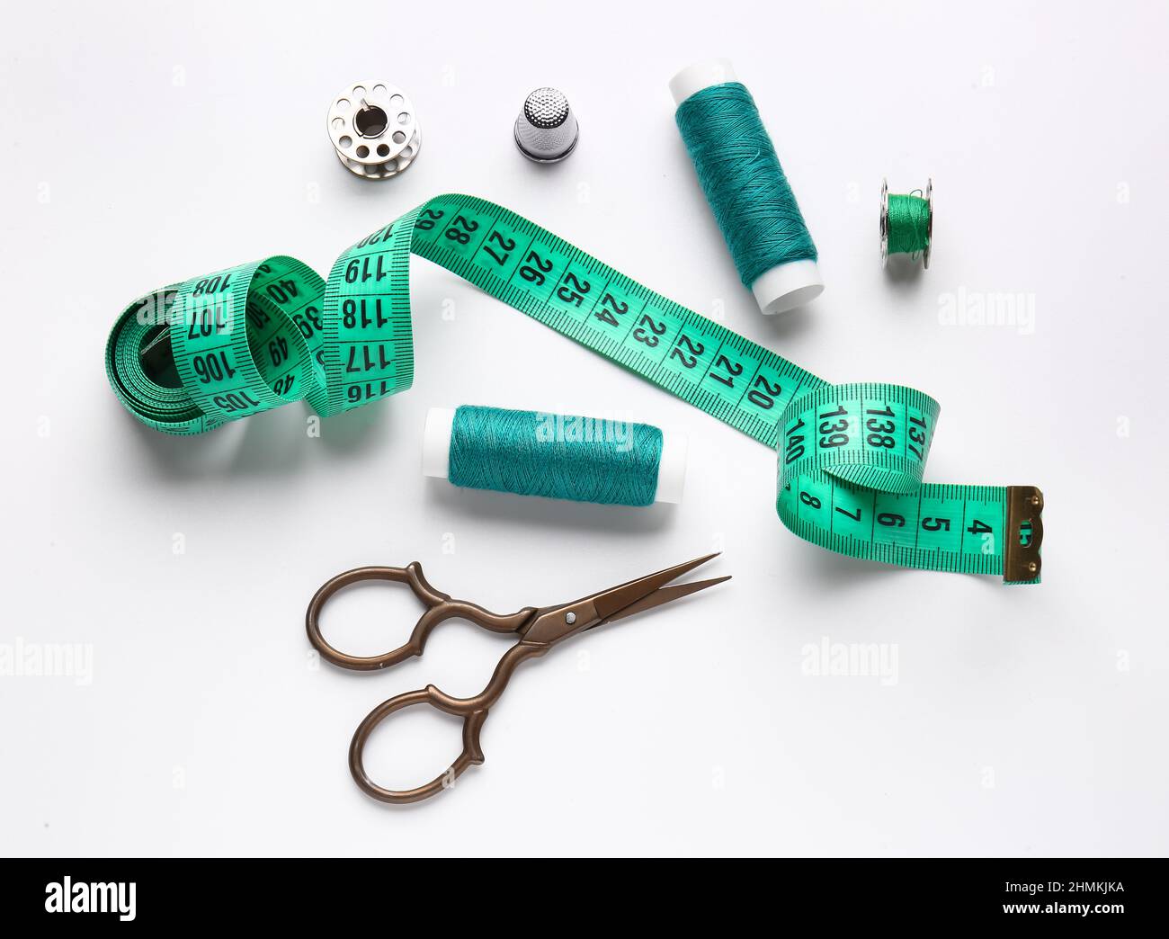 Thread spools with measuring tape and scissors on white background ...