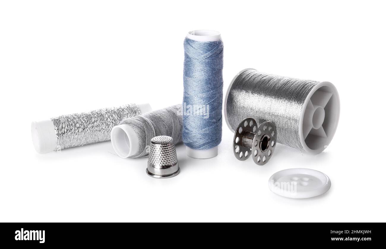 Different thread spools, button and thimble on white background Stock ...