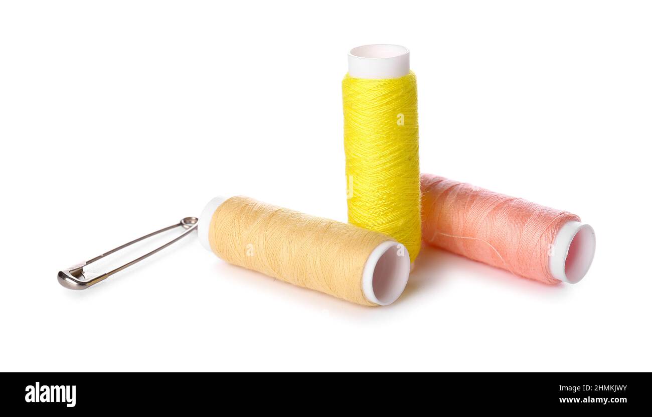 Thread spools and safety pin on white background Stock Photo - Alamy