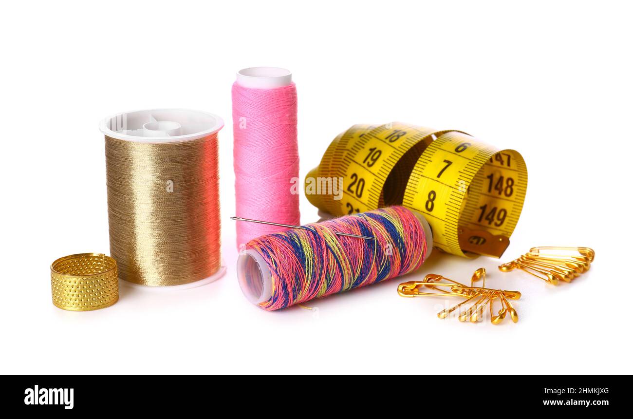 Different thread spools, thimble, measuring tape and safety pins on ...